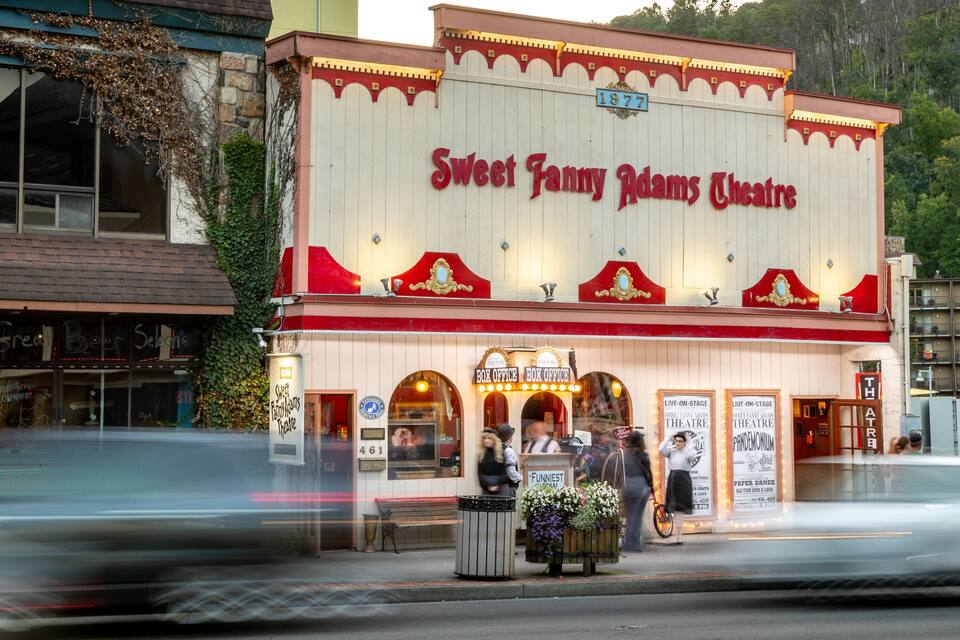 Teatro Sweet Fanny Adams com design vintage, situado numa rua movimentada com carros a passar.