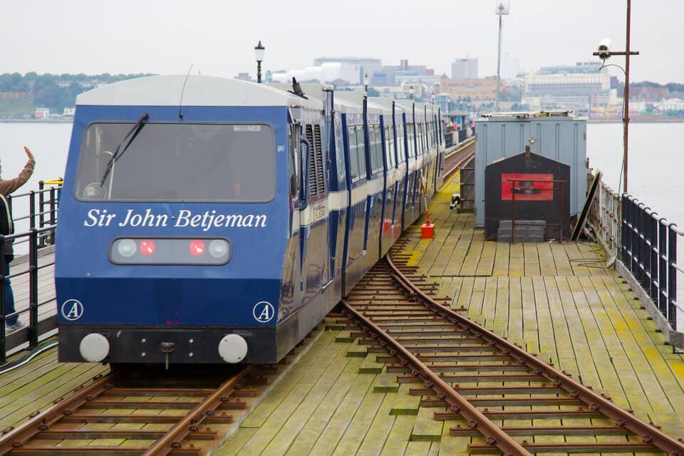 Um trem azul identificado como "Sir John Betjeman" em uma linha férrea.