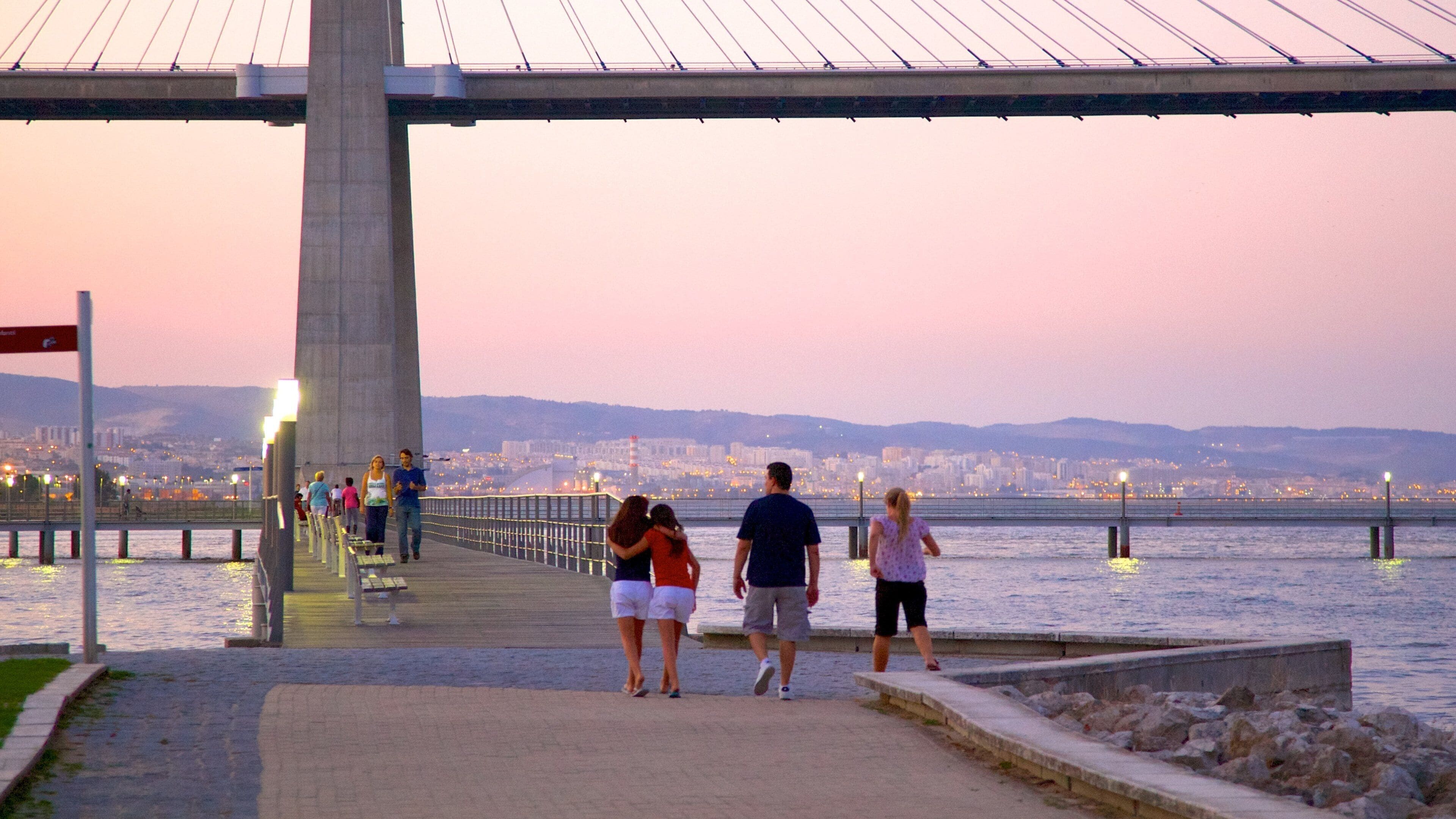Uma ponte com pessoas caminhando em um caminho ao lado de um corpo d'água.