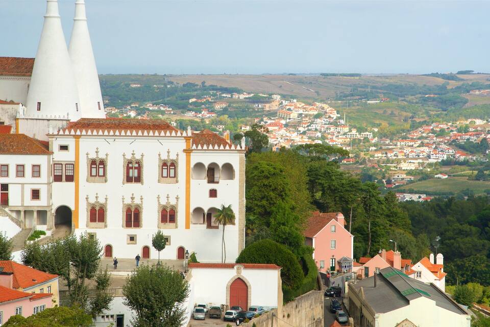 Uma cidade com edifícios brancos, telhados vermelhos e vista para o campo.