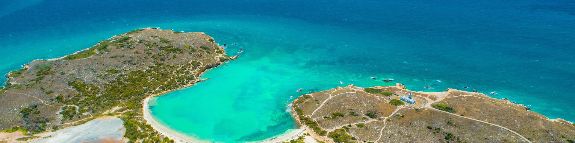 Vista aérea de uma área costeira com águas turquesa cristalinas, uma praia de areia e uma massa de água amarelada bem definida.