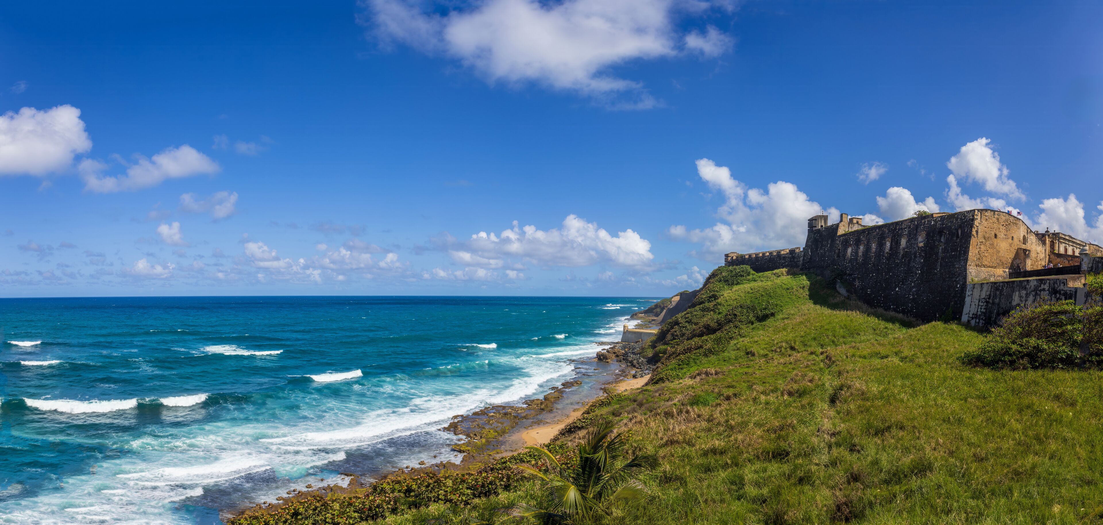 Paisagem costeira com um forte de pedra histórico sobre o oceano.