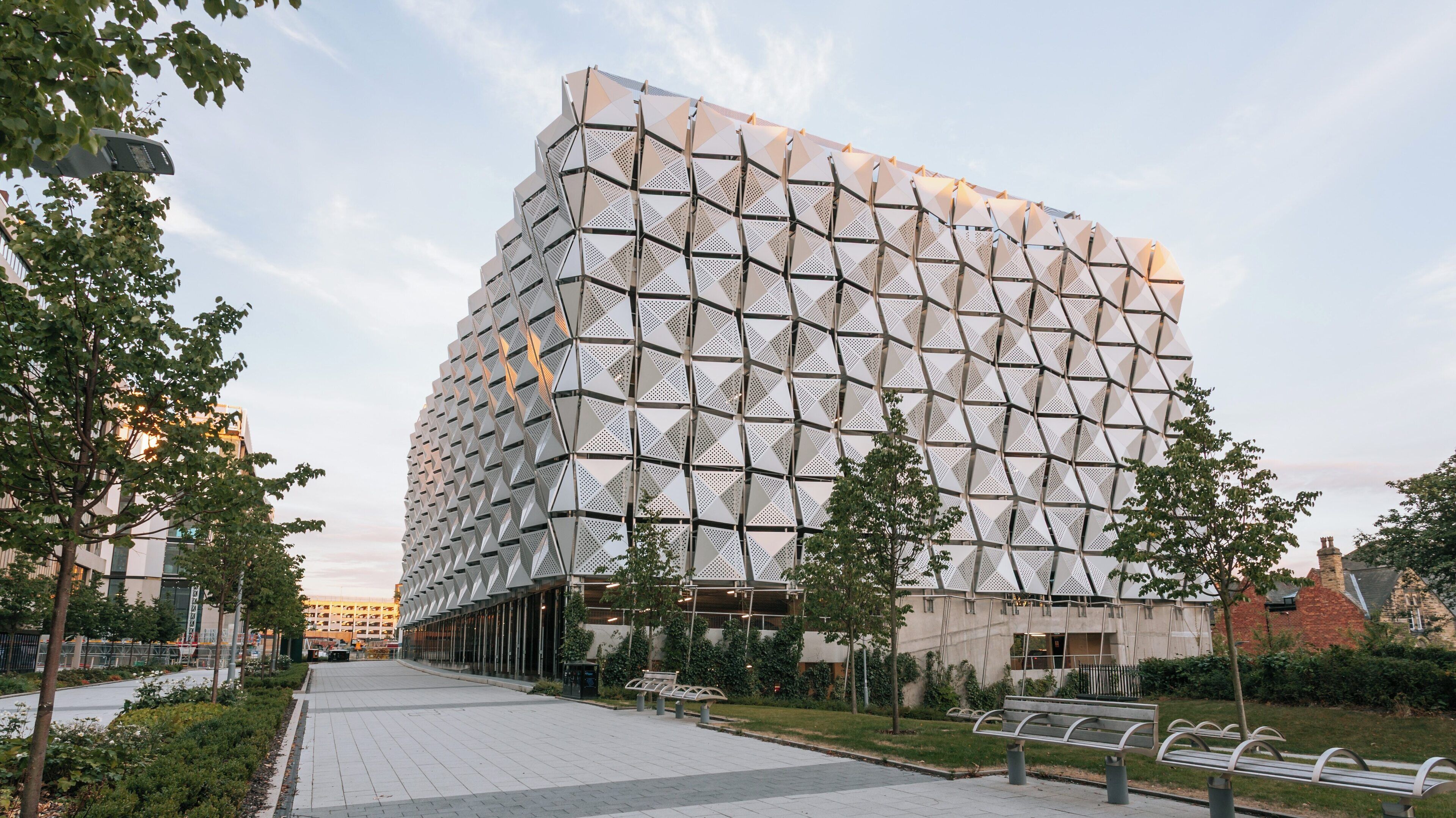 Modern architectural design of a building in the University District of Leeds, England, showcasing innovative structure and urban greenery in evening light