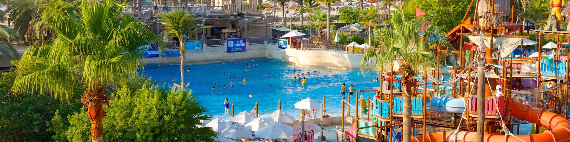 Resort com uma piscina grande, palmeiras e um tobogã.