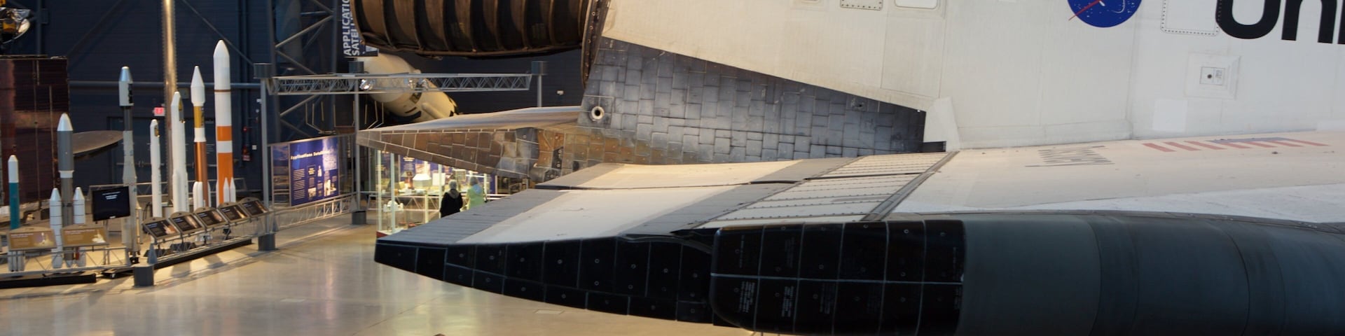 Um ônibus espacial exposto em um museu, com visitantes observando.