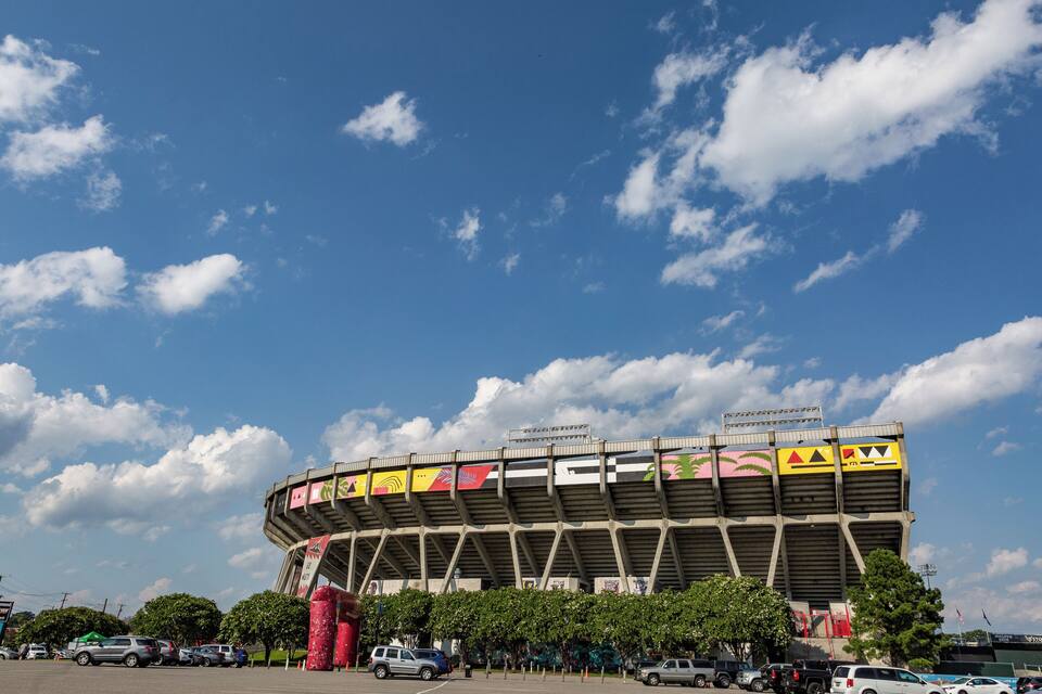 Um estádio grande com faixas coloridas e um céu azul com nuvens.