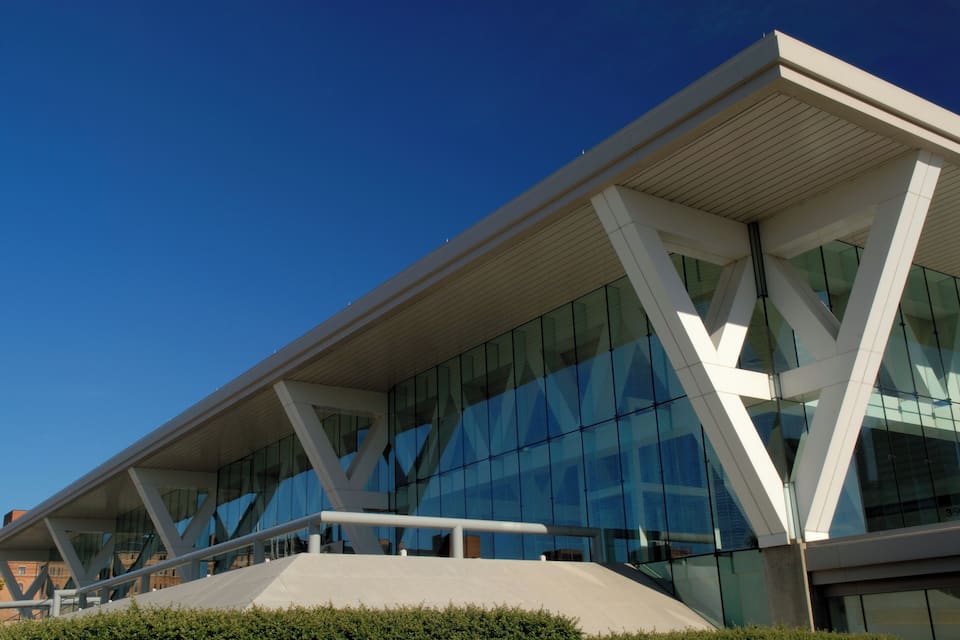 Um edifício moderno com design geométrico, destacando uma estrutura branca e fachada de vidro.