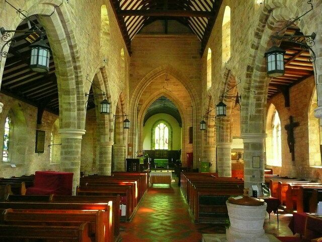 Interior de igreja com tetos em arco, bancos de madeira e paredes de pedra.