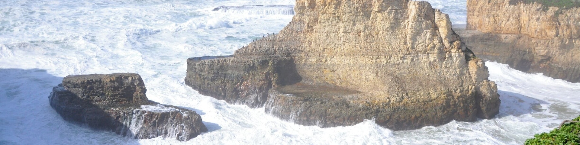 Paisagem costeira com falésias rochosas e ondas quebrando.