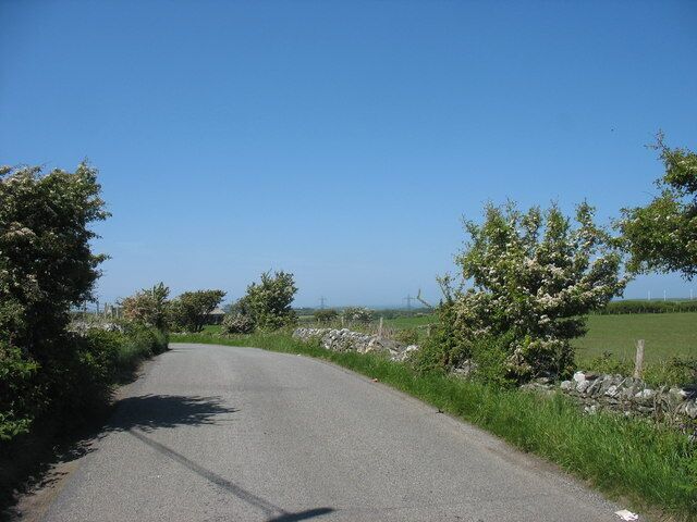 Uma estrada rural com muros de pedra e árvores.