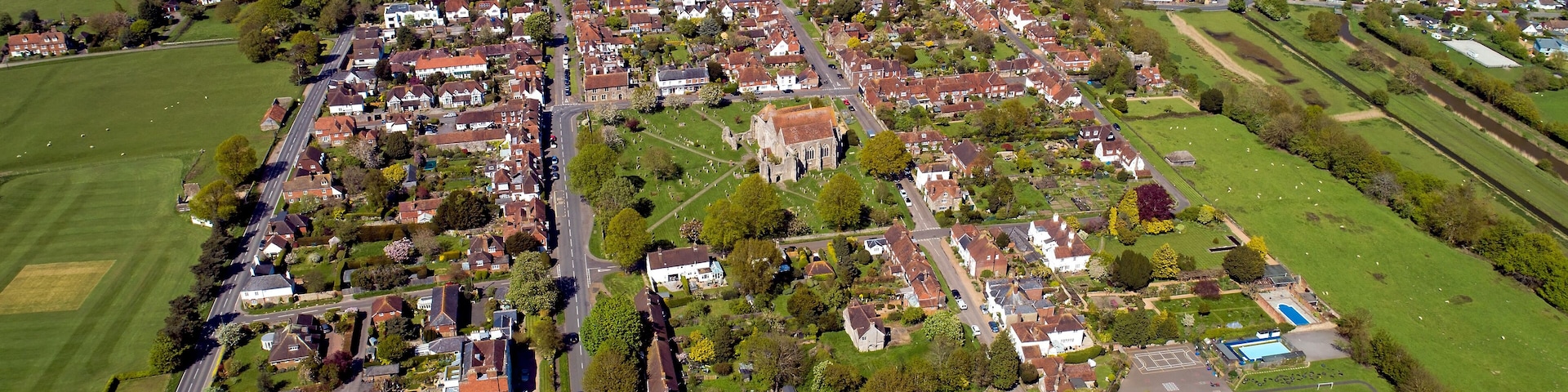 Vista aérea de uma aldeia rural com casas, campos e uma igreja.