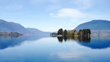 Um lago tranquilo com uma pequena ilha no centro, rodeado por montanhas.