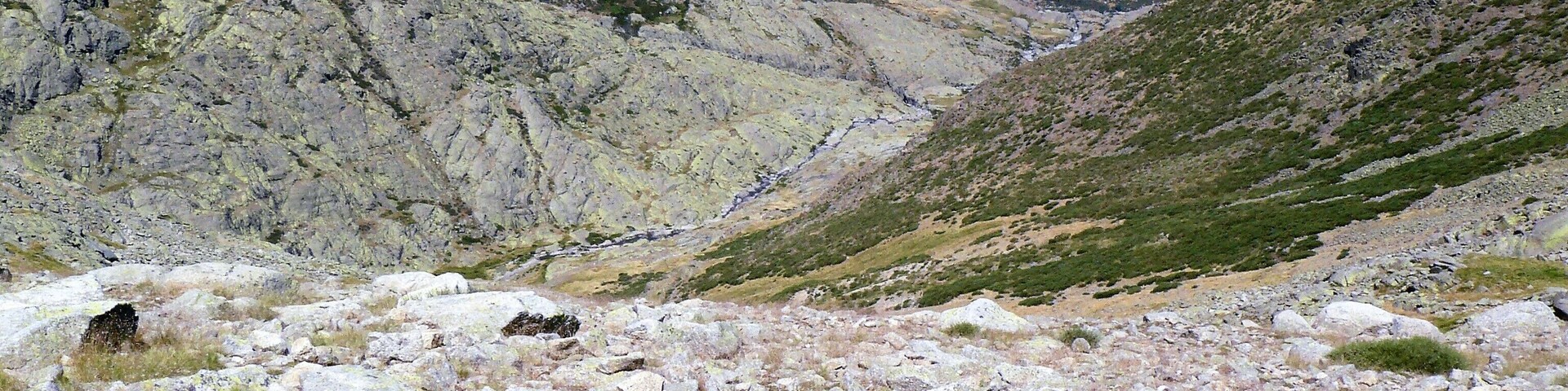 Paisagem montanhosa acidentada, com terreno rochoso e vegetação escassa.