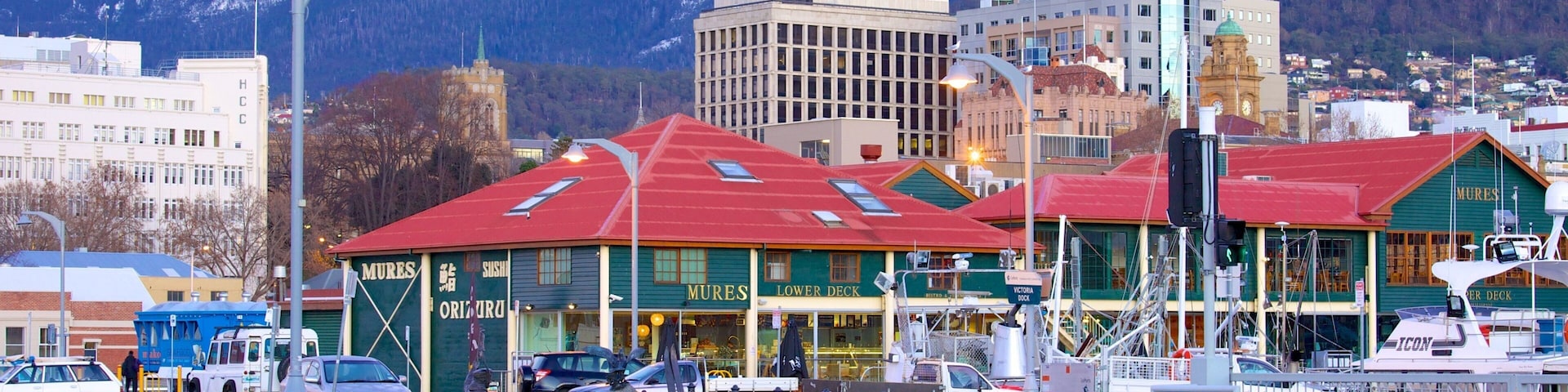 Uma área à beira-mar com um edifício de telhado vermelho identificado como 'MURES' e 'SUSHI ORIZURU'.