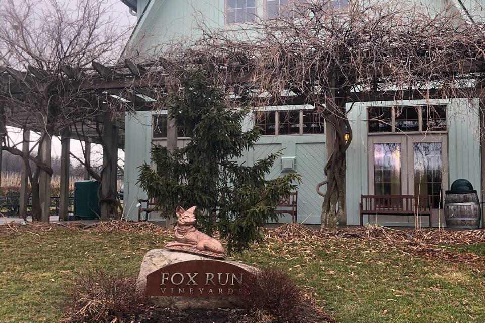 Um edifício azul claro com uma placa de pedra que diz "FOX RUN VINEYARDS".