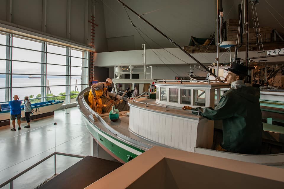 Museu marítimo com exposição de bote salva-vidas e figura vestida de faroleiro.