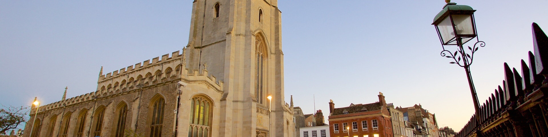 Uma igreja histórica com uma torre alta e janelas em arco, rodeada por ruas de paralelepípedos e edifícios tradicionais.
