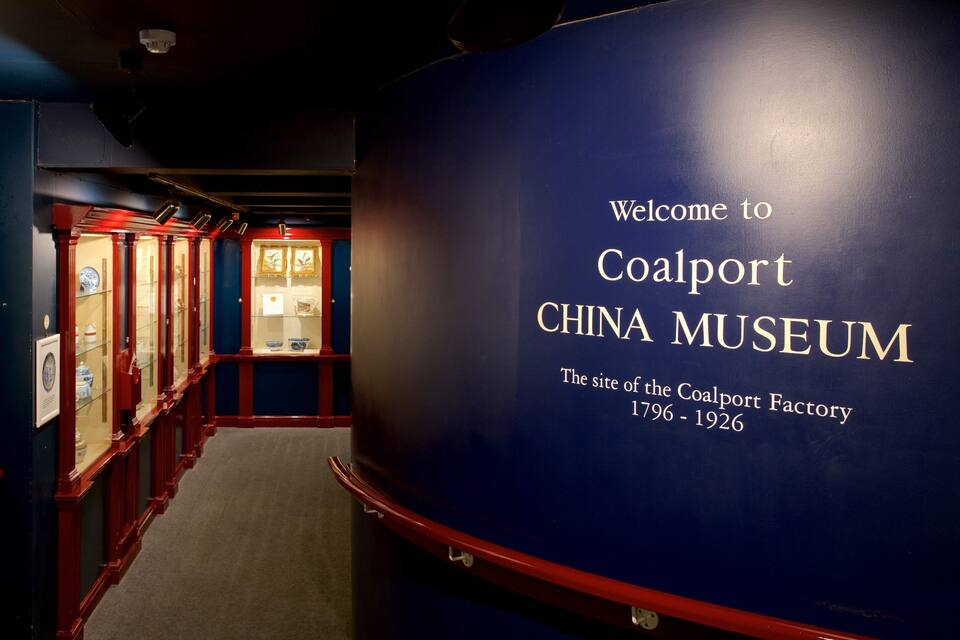 Corredor com vitrines e uma grande parede azul com o texto 'Welcome to Coalport China Museum'.