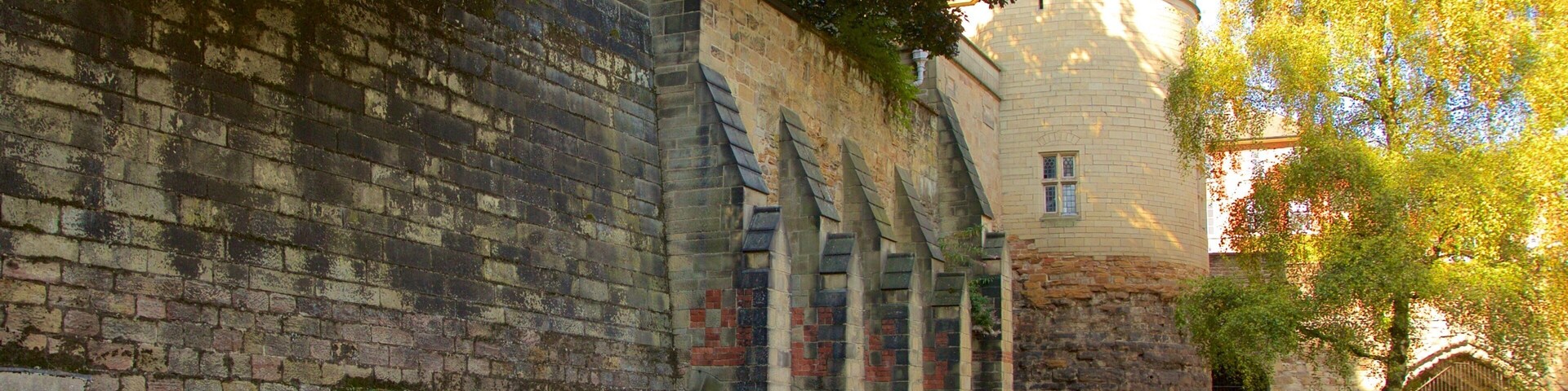 Um edifício histórico de pedra com janelas em arco e uma torre.