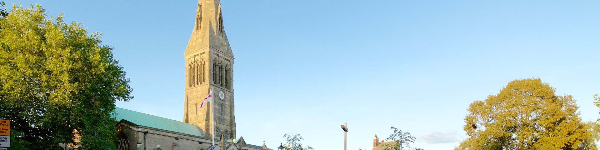 Uma igreja com uma torre alta, um campanário e um portão de tijolos vermelhos.
