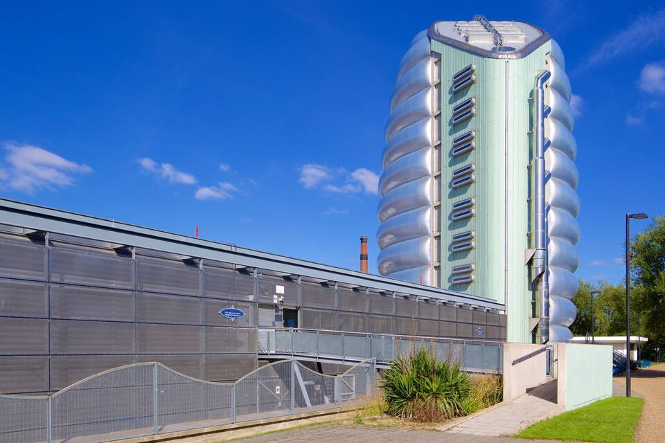 Um edifício moderno de estilo industrial com estrutura cilíndrica e um anexo com telhado plano.