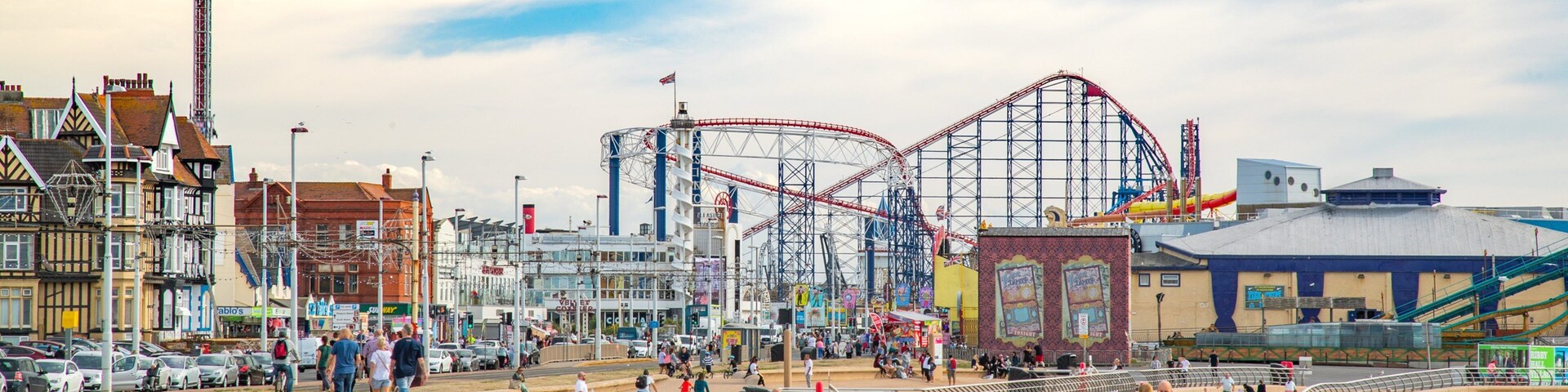 Um parque de diversões à beira-mar, com montanhas-russas e uma roda gigante.