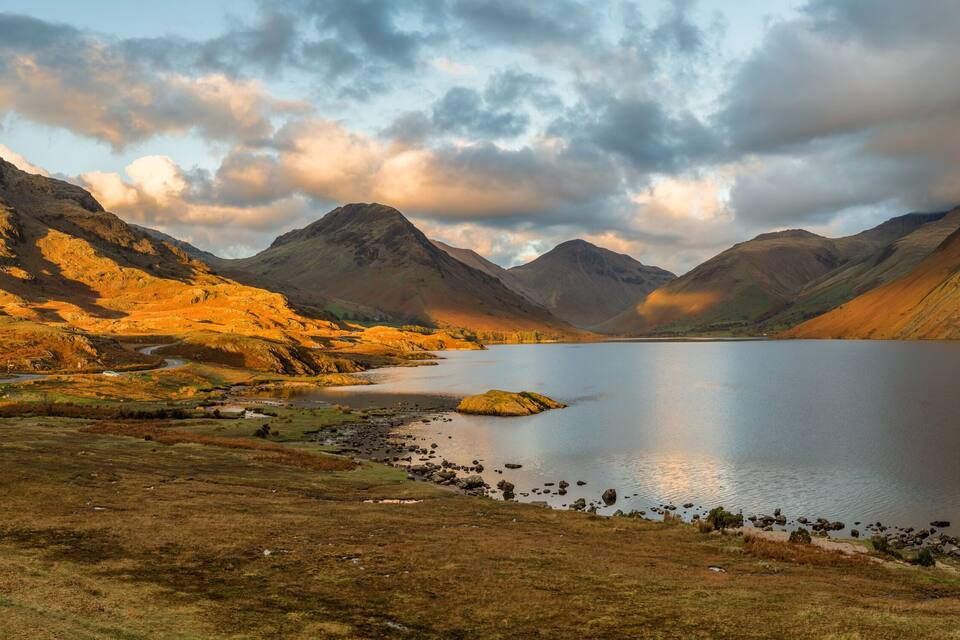 Paisagem montanhosa com um lago e uma estrada sinuosa.