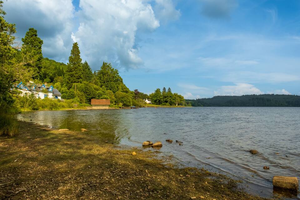 Vista de um lago com casas, árvores e céu claro.