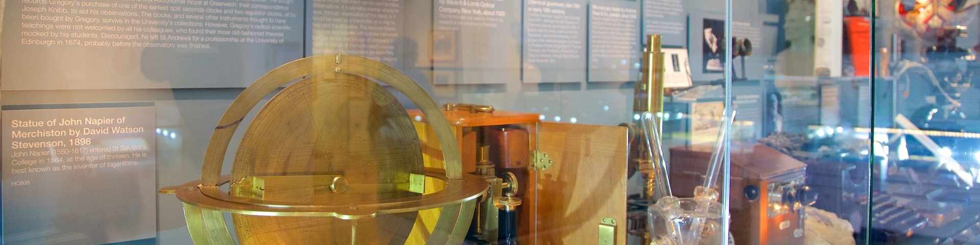 Um instrumento astronômico de bronze, possivelmente um telescópio, exposto em uma vitrine de museu.