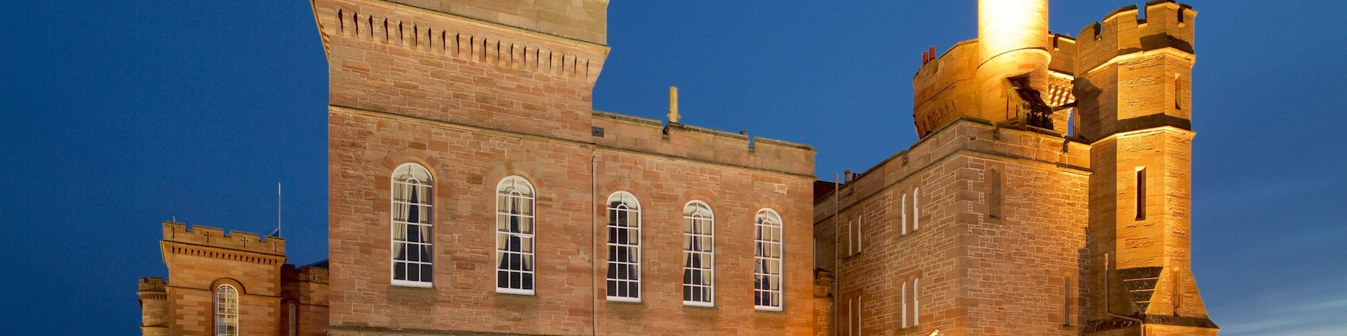 Um edifício histórico de tijolos com janelas em arco e uma torre imponente.
