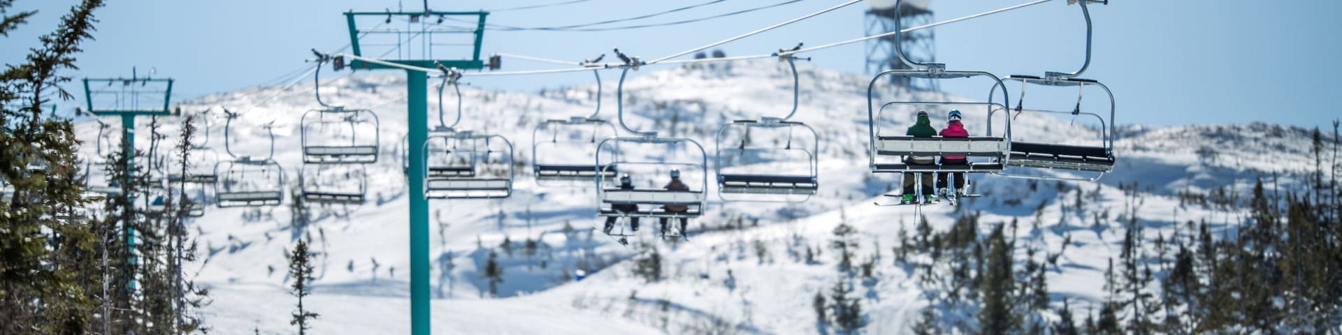 Um teleférico com esquiadores e snowboarders numa encosta nevada de montanha.