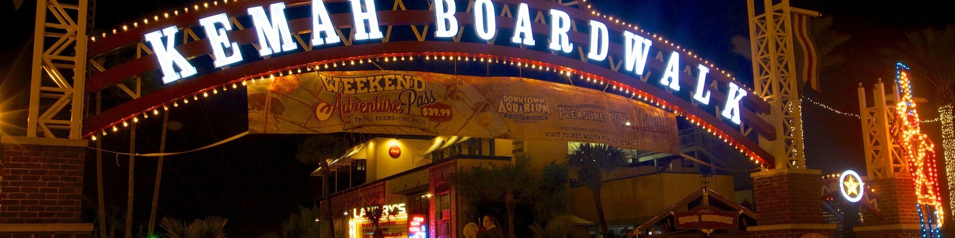 Entrada do Boardwalk de Kemah, com placas iluminadas e uma carruagem puxada por cavalos.