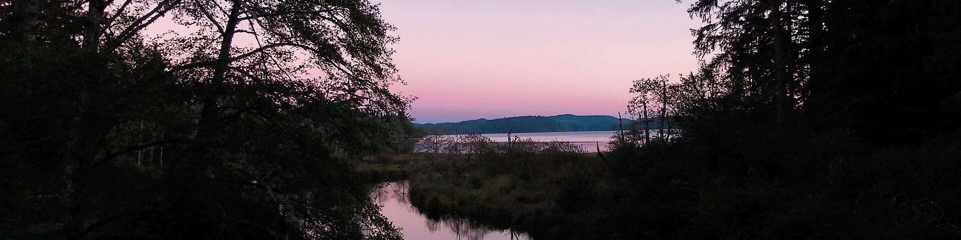As promised, another sunset to finish off the day.
The trail that begins at Ozette Lake is billed as a 10.5 mile triangle which leads you down to the ocean and across a couple of miles of beach.
But, practically speaking, you need to find a way to navigate the surf unless you hit the beach at very low tide. Our hike stretched out for about 12 miles, as we made serpentine patterns through the exposed rocks out and back to see all the sea stacks.
When we returned to the lake, the sun had all but rolled over the lip of the earth. But it left a few colors dangling in the air, and Ozette Lake caught them all and tossed them back up like a smooth and silky sheet of glass.