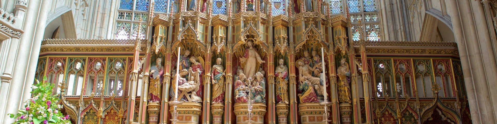 Um altar ricamente decorado com estátuas religiosas e vitrais.