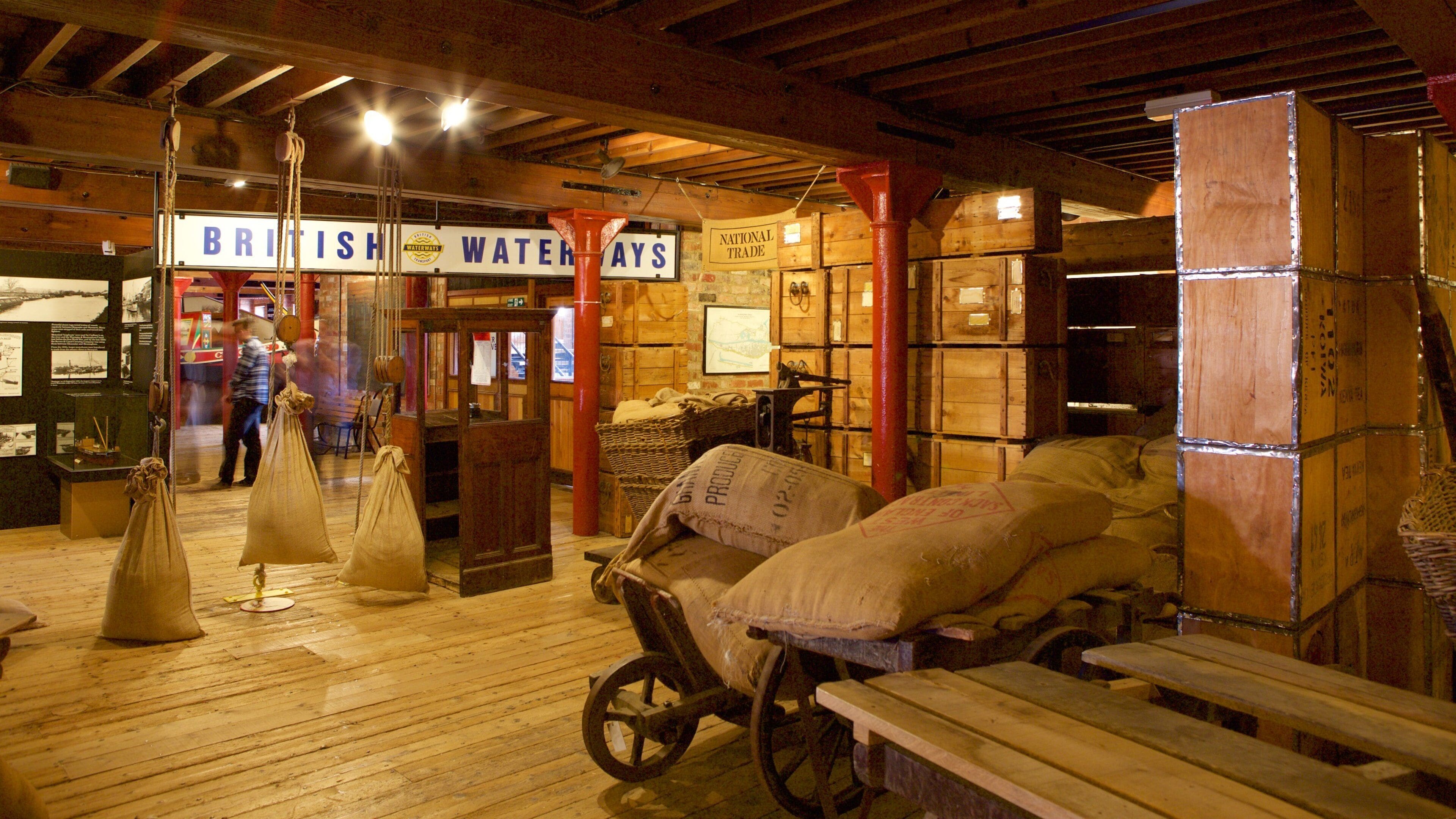 Uma exposição histórica com caixotes de madeira, uma roda d'água e um letreiro com a inscrição 'BRITISH WATERWAYS'.