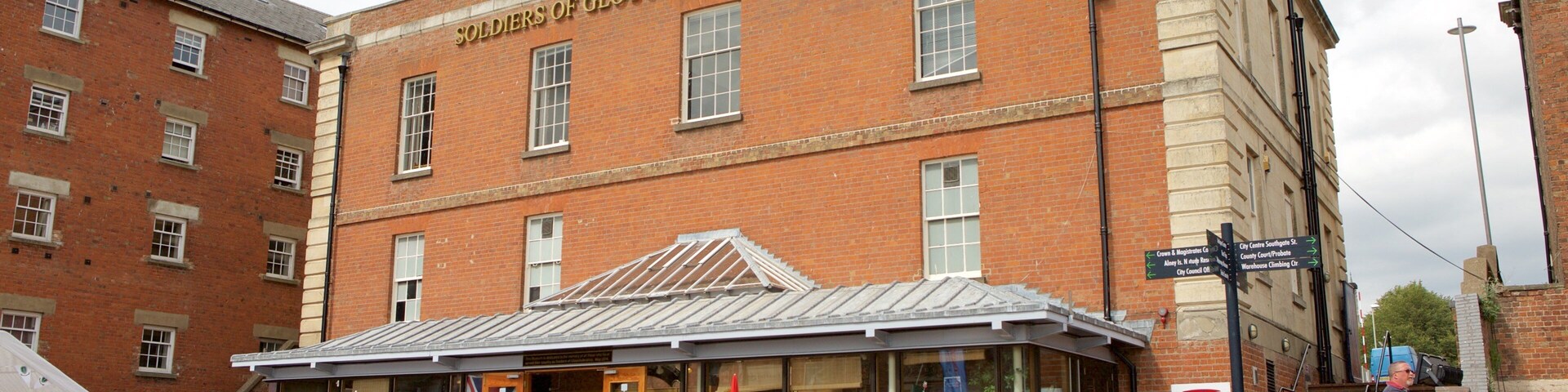 Edifício do Museu dos Soldados de Gloucestershire com pessoas sentadas do lado de fora.