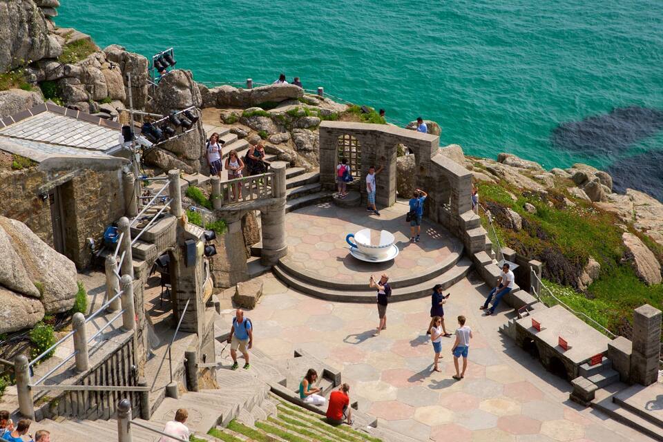 Um sítio histórico com uma estrutura de pedra circular, degraus e vista para o mar.