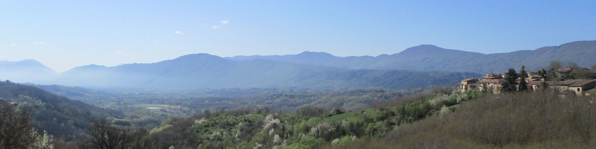 Paisagem montanhosa com uma aldeia aninhada entre as colinas.