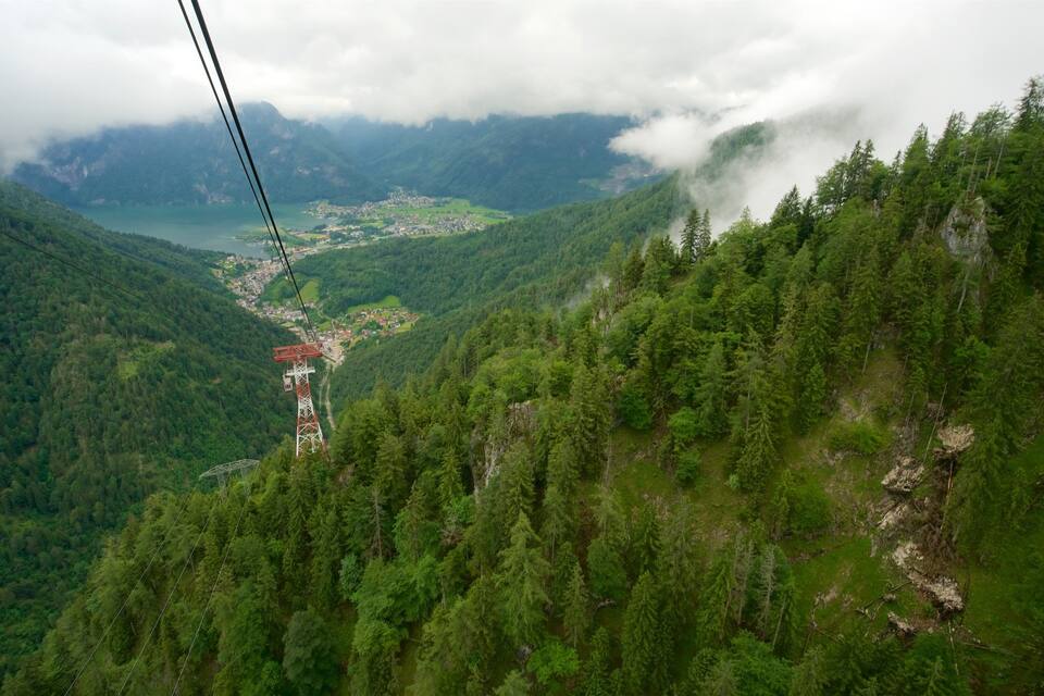 Um sistema de teleférico numa área montanhosa com florestas densas e um vale abaixo.