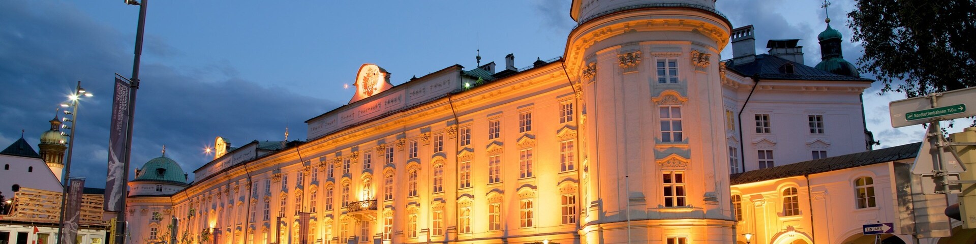 Um edifício histórico com cúpula verde e arquitetura clássica, iluminado ao entardecer.