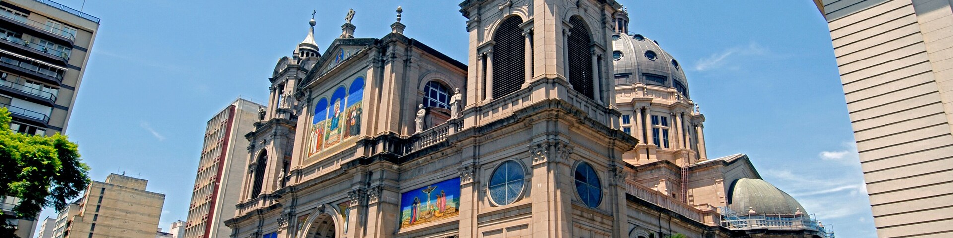 Uma catedral histórica com uma torre de sino, janelas amplas e uma cúpula.