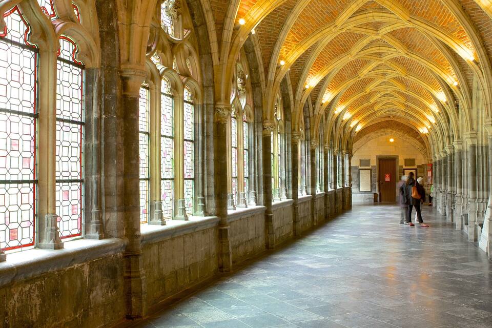 Nave de uma catedral com tetos abobadados e vitrais.