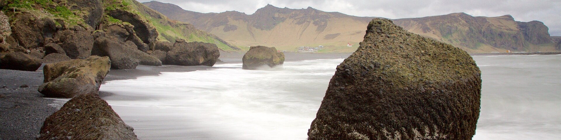 Uma costa rochosa com grandes pedras e um mar calmo.