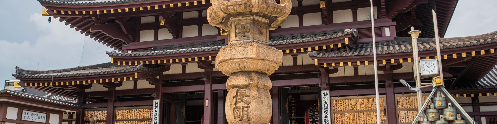 Um edifício japonês tradicional com uma estátua de pedra em frente.