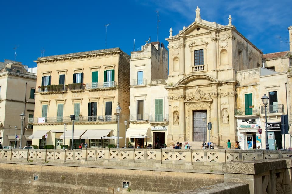 Um edifício histórico com arquitetura elaborada, uma ponte de pedra e um céu azul límpido.
