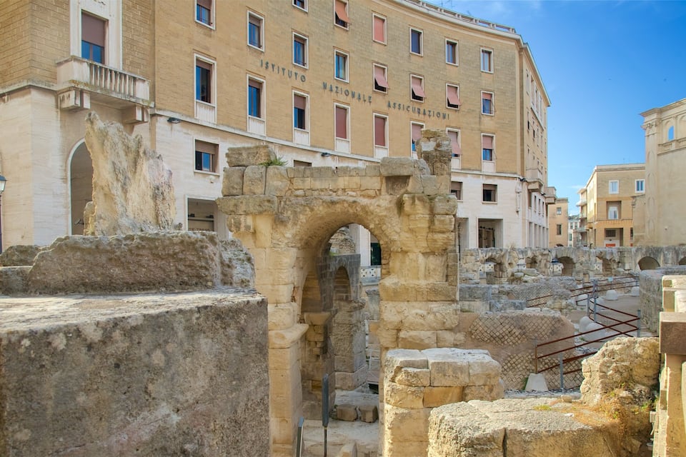Ruínas antigas com arcos e colunas de pedra, rodeadas por edifícios modernos.