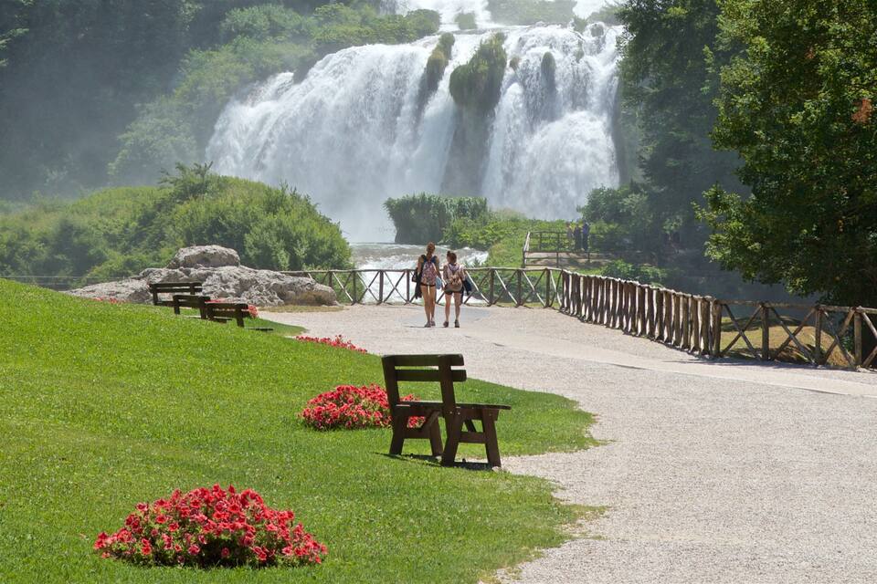 Uma cascata, bancos e um caminho que a leva até lá.