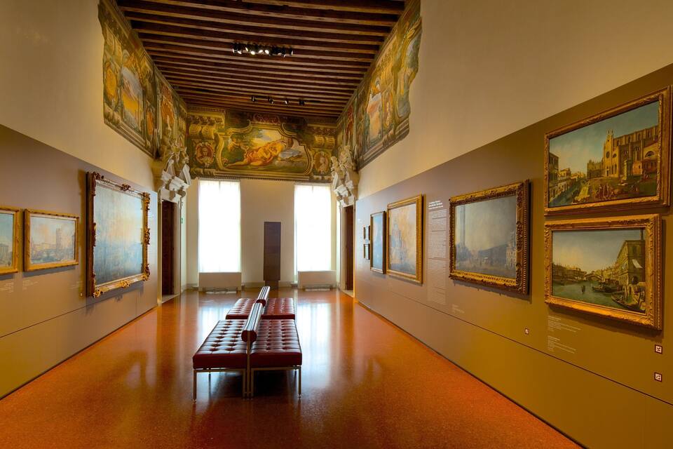 Um corredor de museu com pinturas clássicas e um banco no centro.