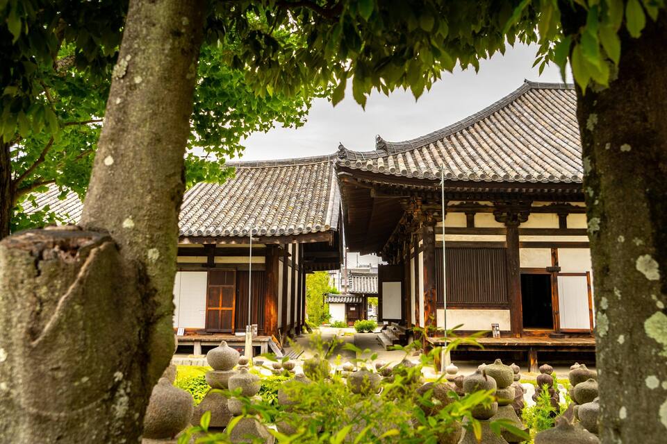 Arquitetura japonesa tradicional com telhados em telhas, estruturas de madeira e lanternas de pedra.
