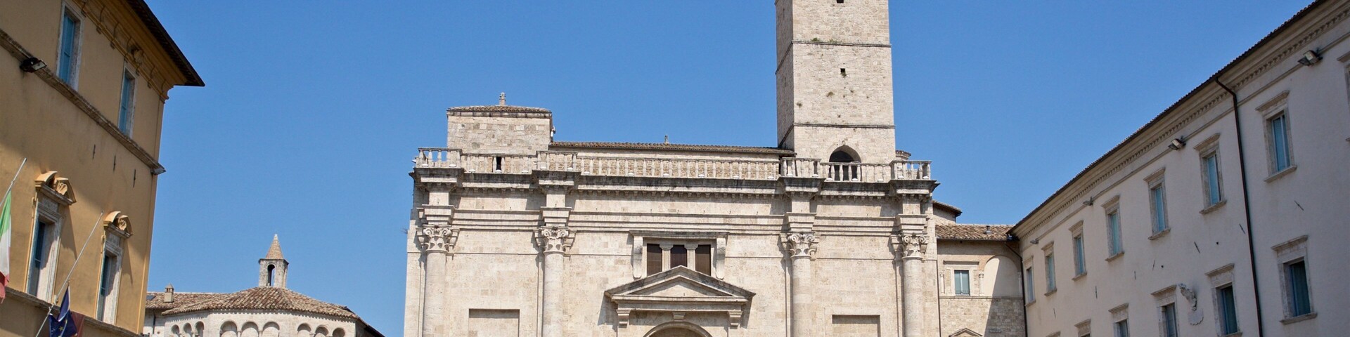 Uma igreja histórica com uma torre de sino alta e uma grande entrada em arco.